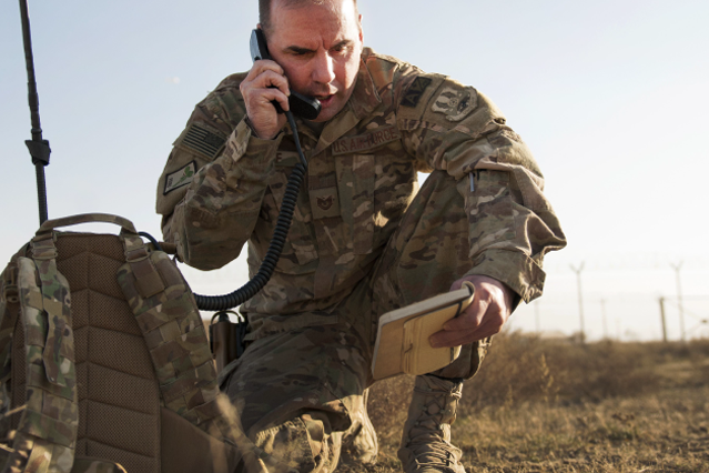 Military man training in the field on a phone.