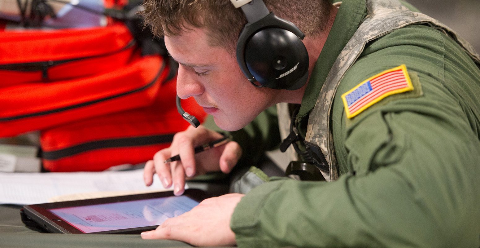 Student using a tablet at a desk wearing headphones.